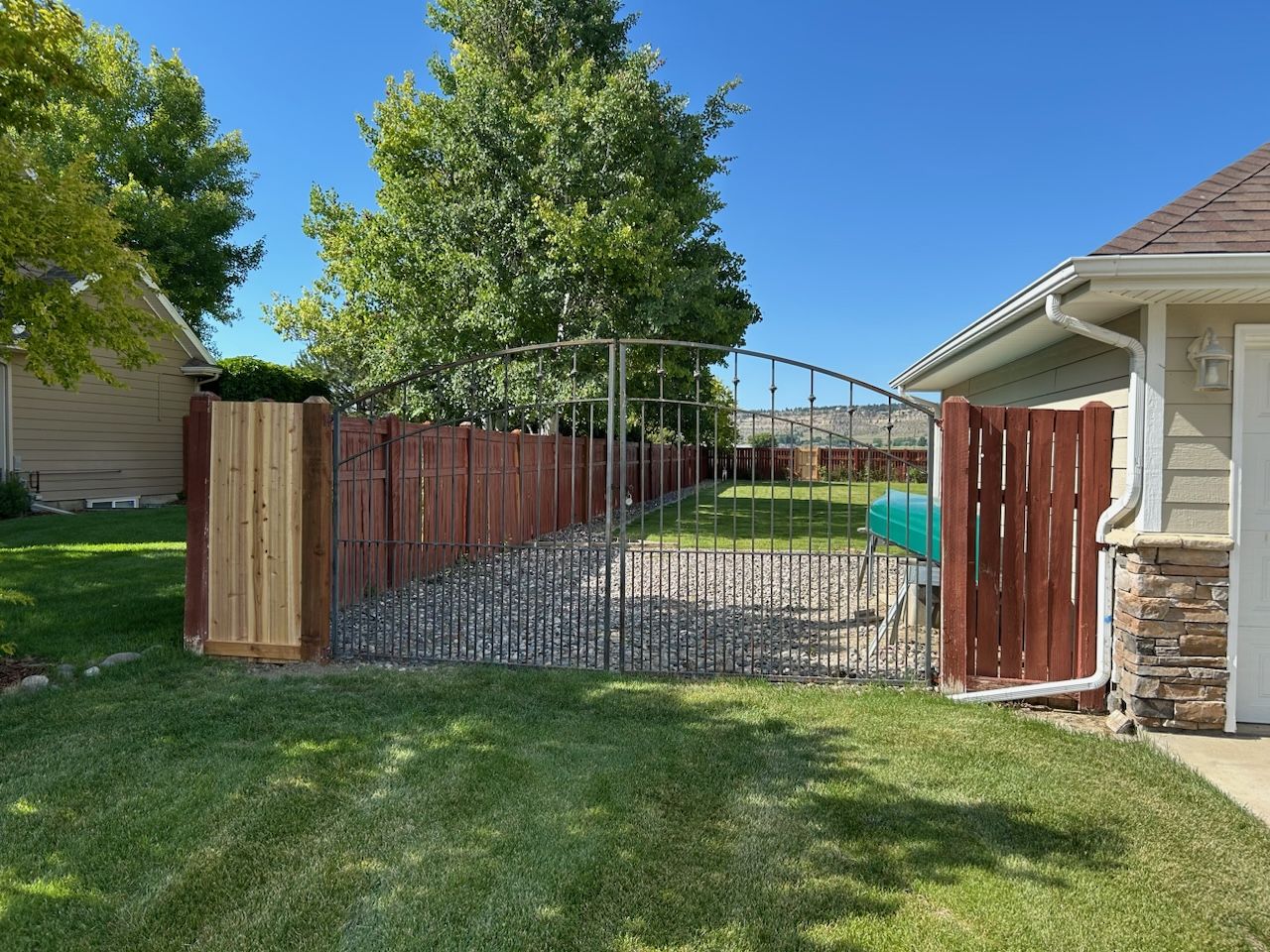Elegant Iron Double Gate and Sturdy Wood Fence | H & H Fence MT LLC